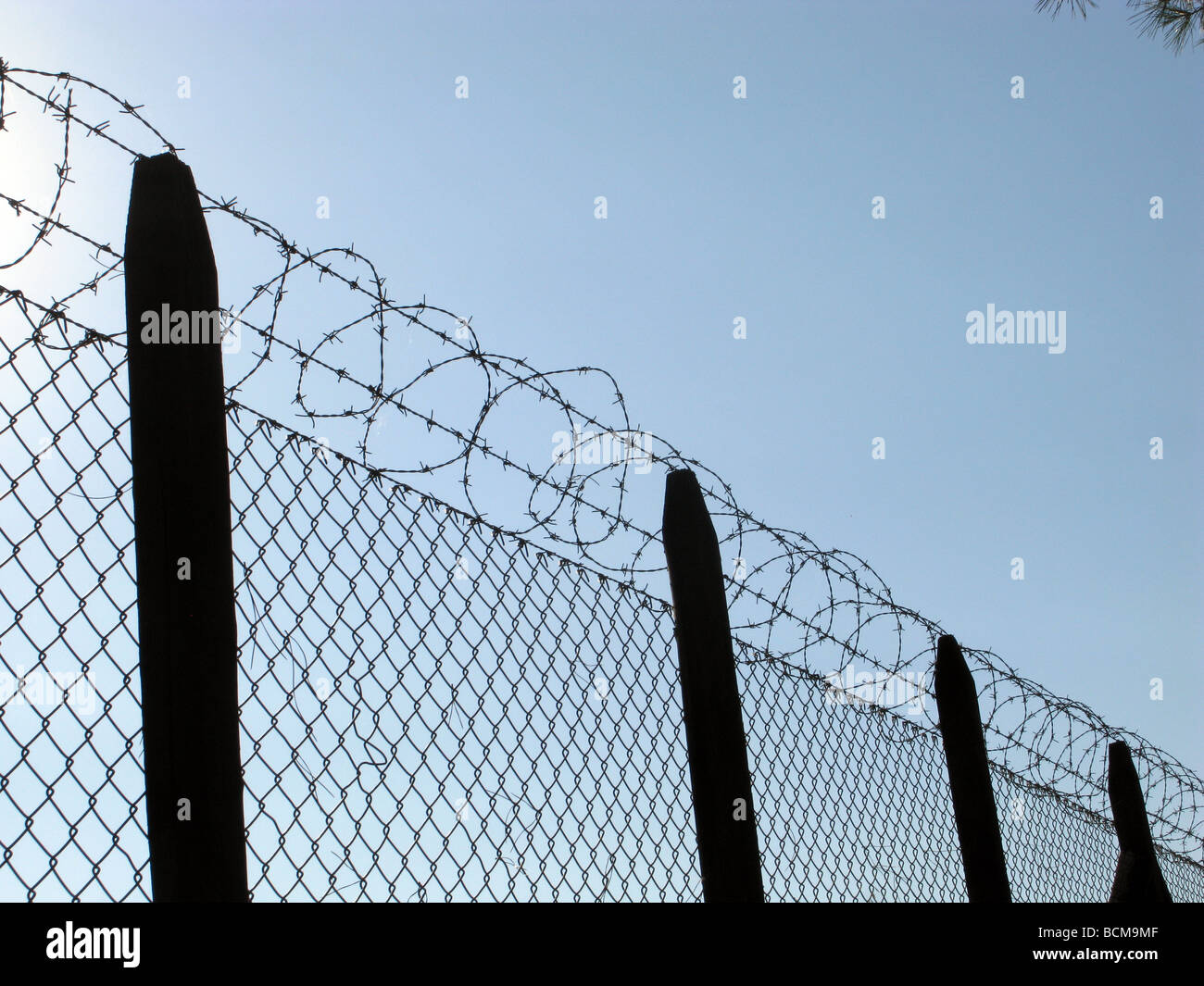 dark high wall fence with barbed wire outdoors Stock Photo - Alamy