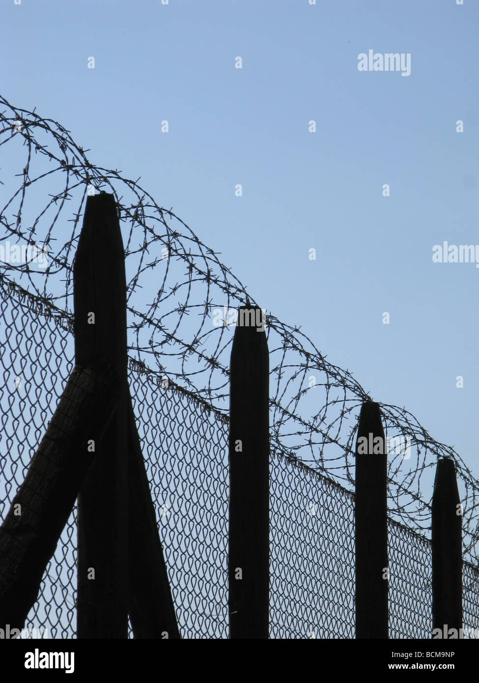 dark high wall fence with barbed wire outdoors Stock Photo - Alamy