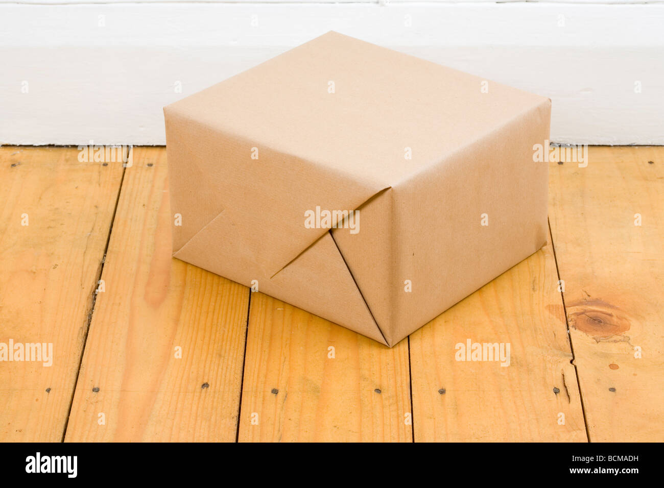 A brown paper parcel on a wooden floor Stock Photo - Alamy