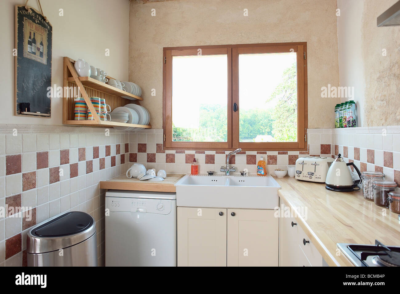 Window above sink and dishwasher in small economy-style kitchen with ...