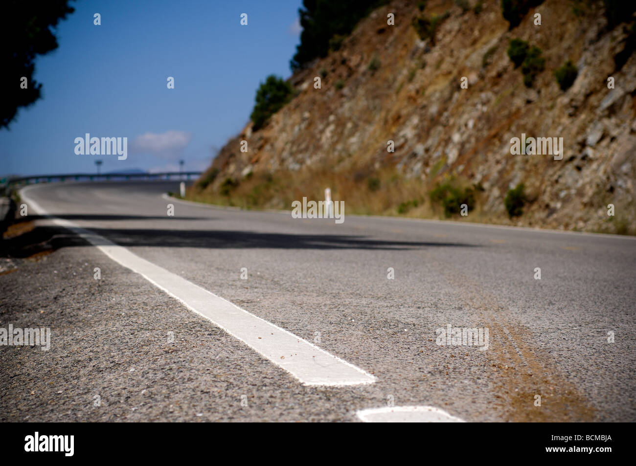 A small depth of field focuses on a road marking on a winding road up ...