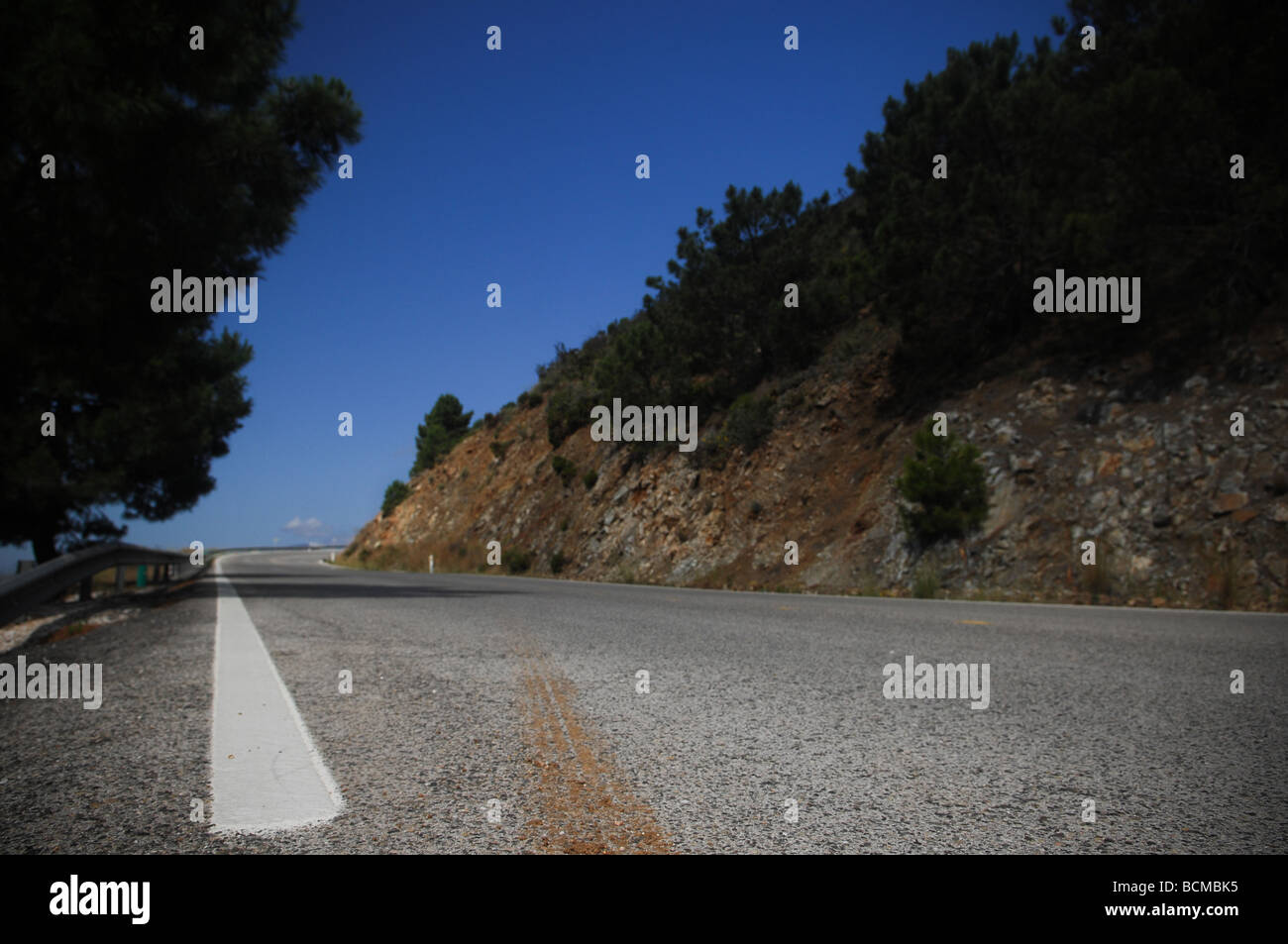 A small depth of field focuses on a road marking on a winding road up ...