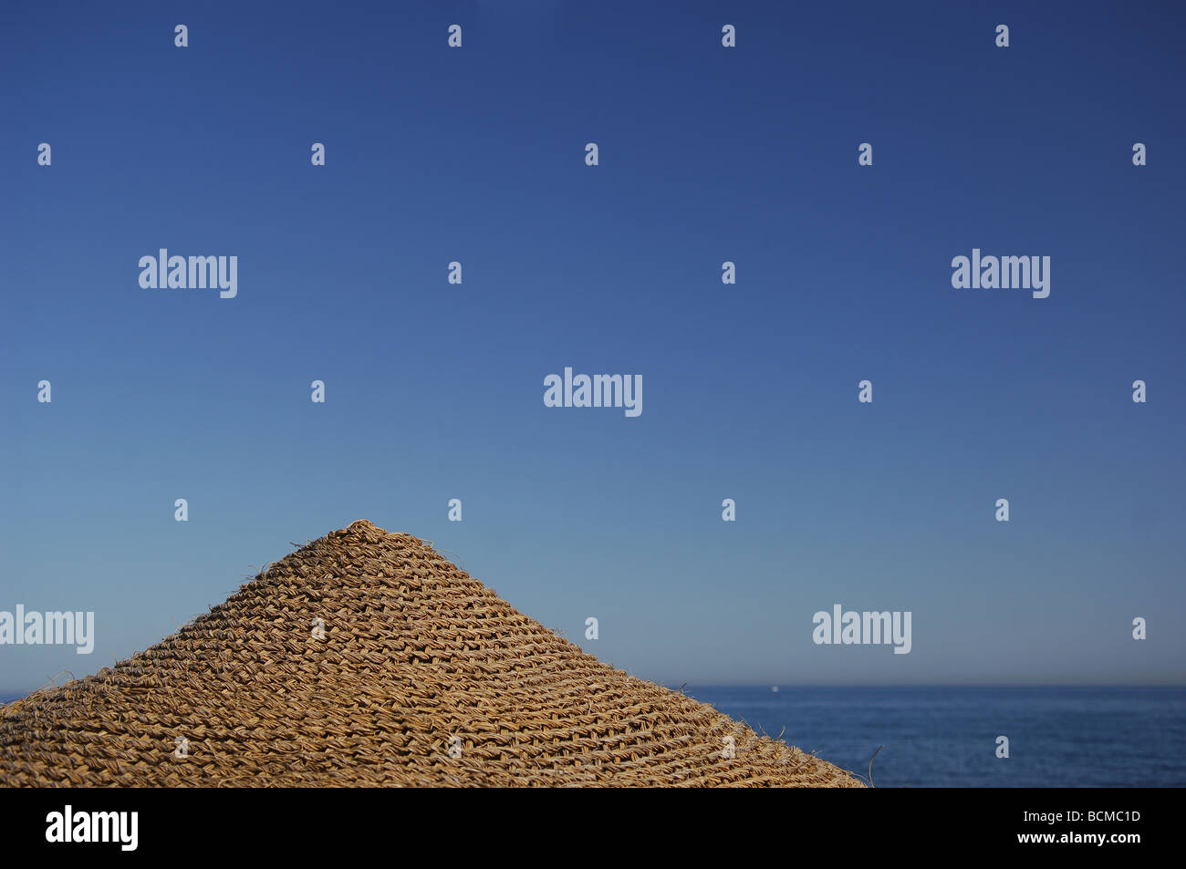 A hessian sun shade against a blue sky and seascape horizon Stock Photo ...