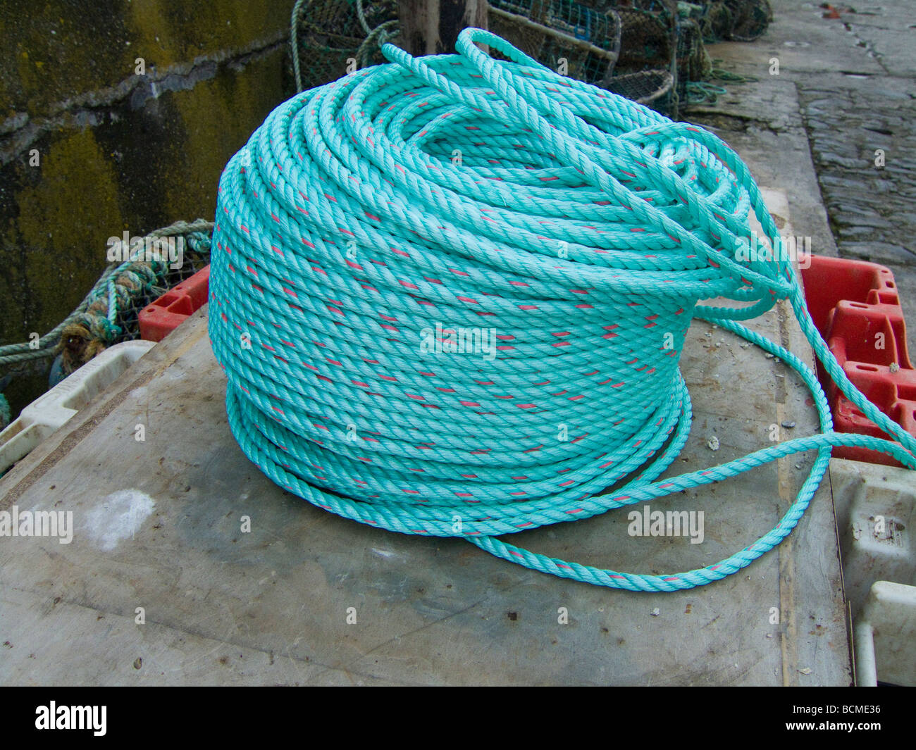 A coil of new blue green rope on the quayside Stock Photo - Alamy