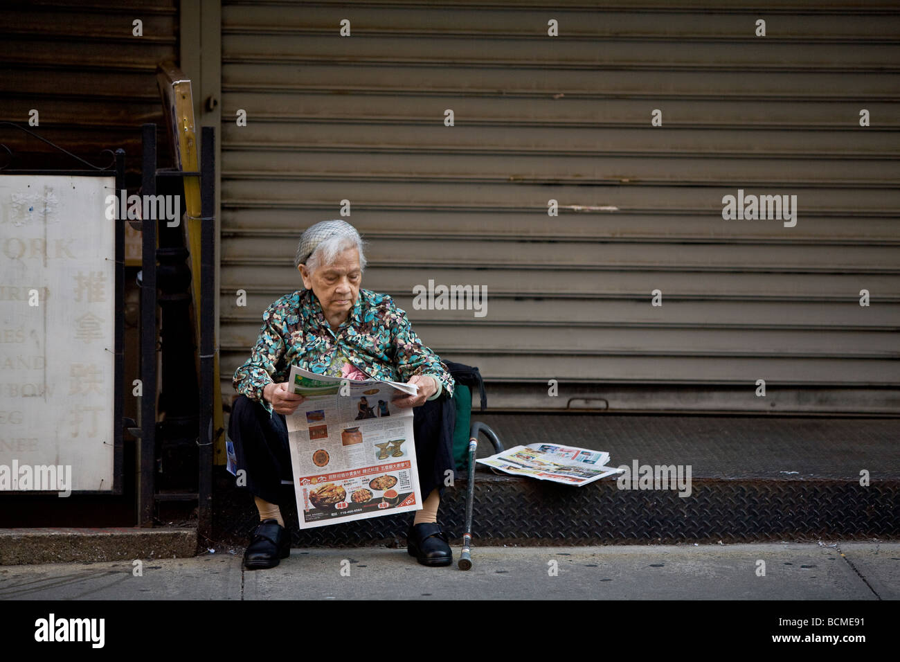 Elder woman reading Chinese news-paper, Chinatown, Manhattan, NY, USA ...