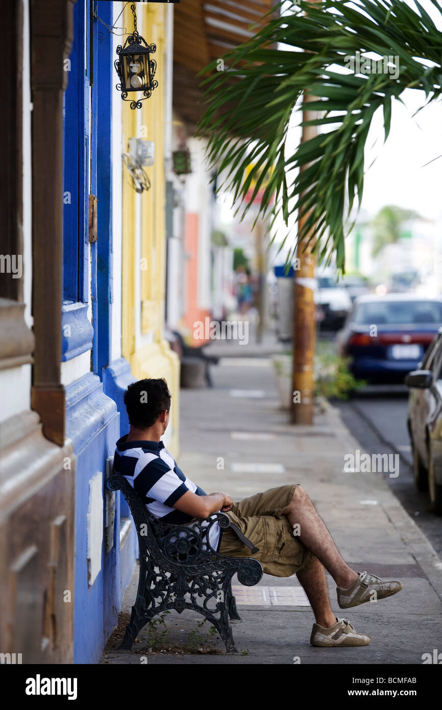 A male sits on one of a row of benches on Calle Real in Liberia's ...