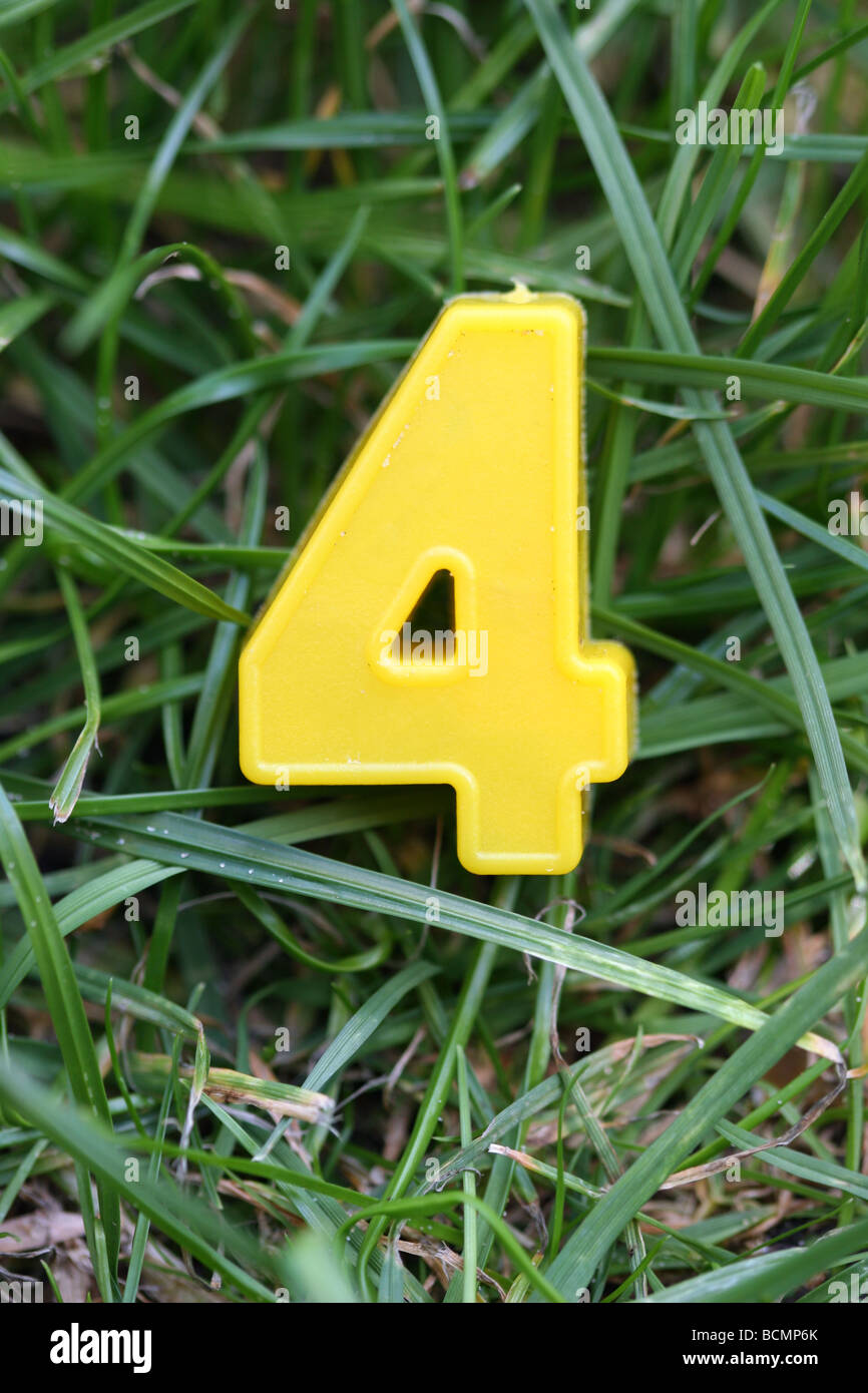 Yellow fridge magnet number four lying on grass Stock Photo - Alamy