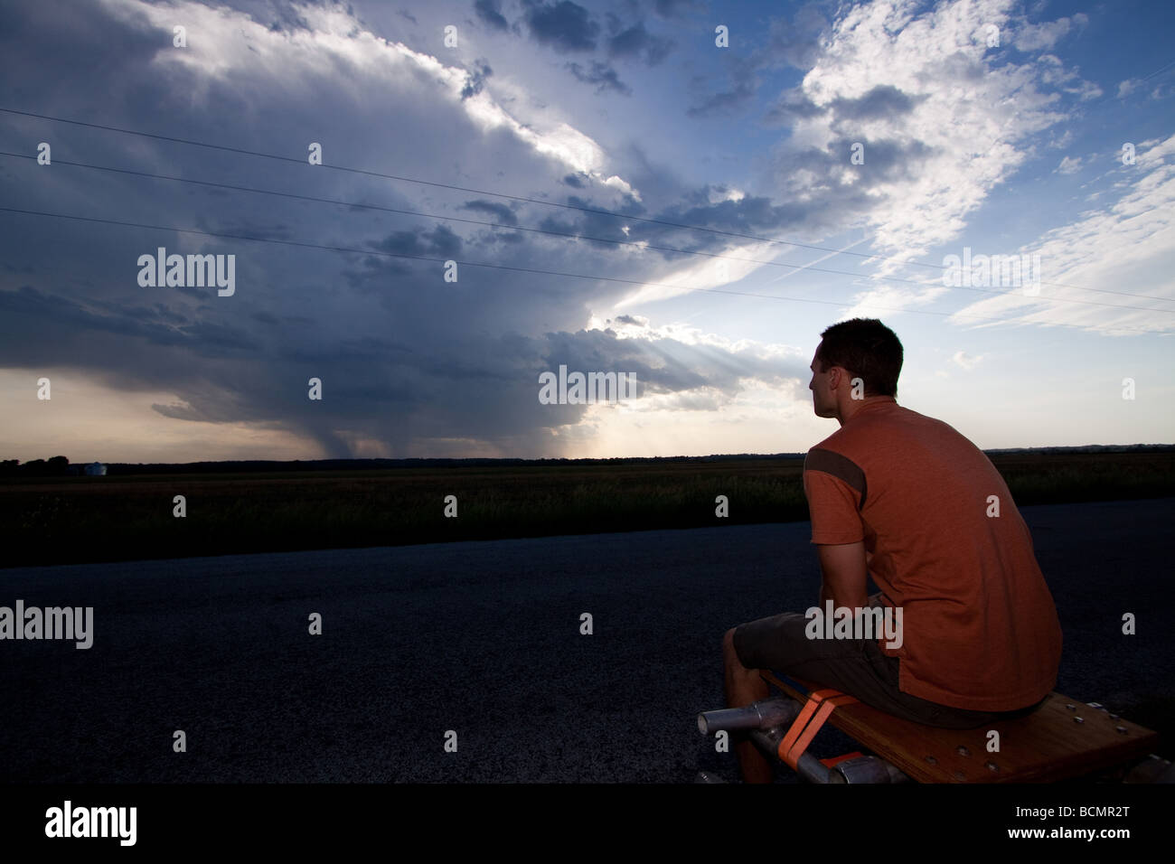 A storm chaser sits atop a car waiting for a storm to develop in ...