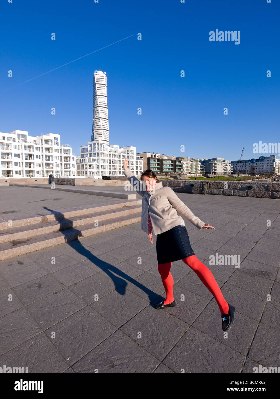 A happy young woman in front of the Turning Torso at the Vastra Hamnen ...