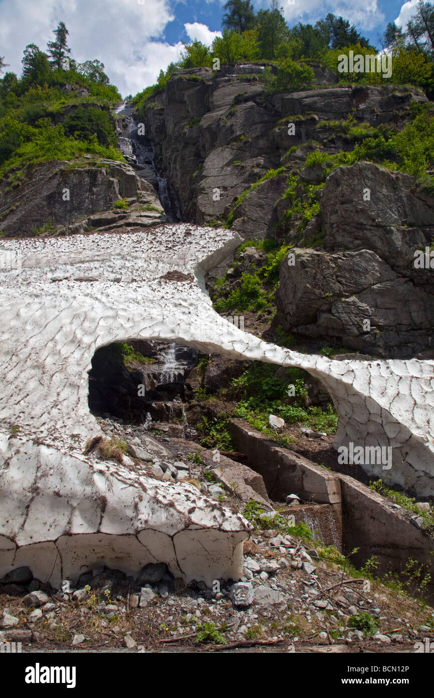 Mountain Stream flowing through the melting remains of avalanche snow ...