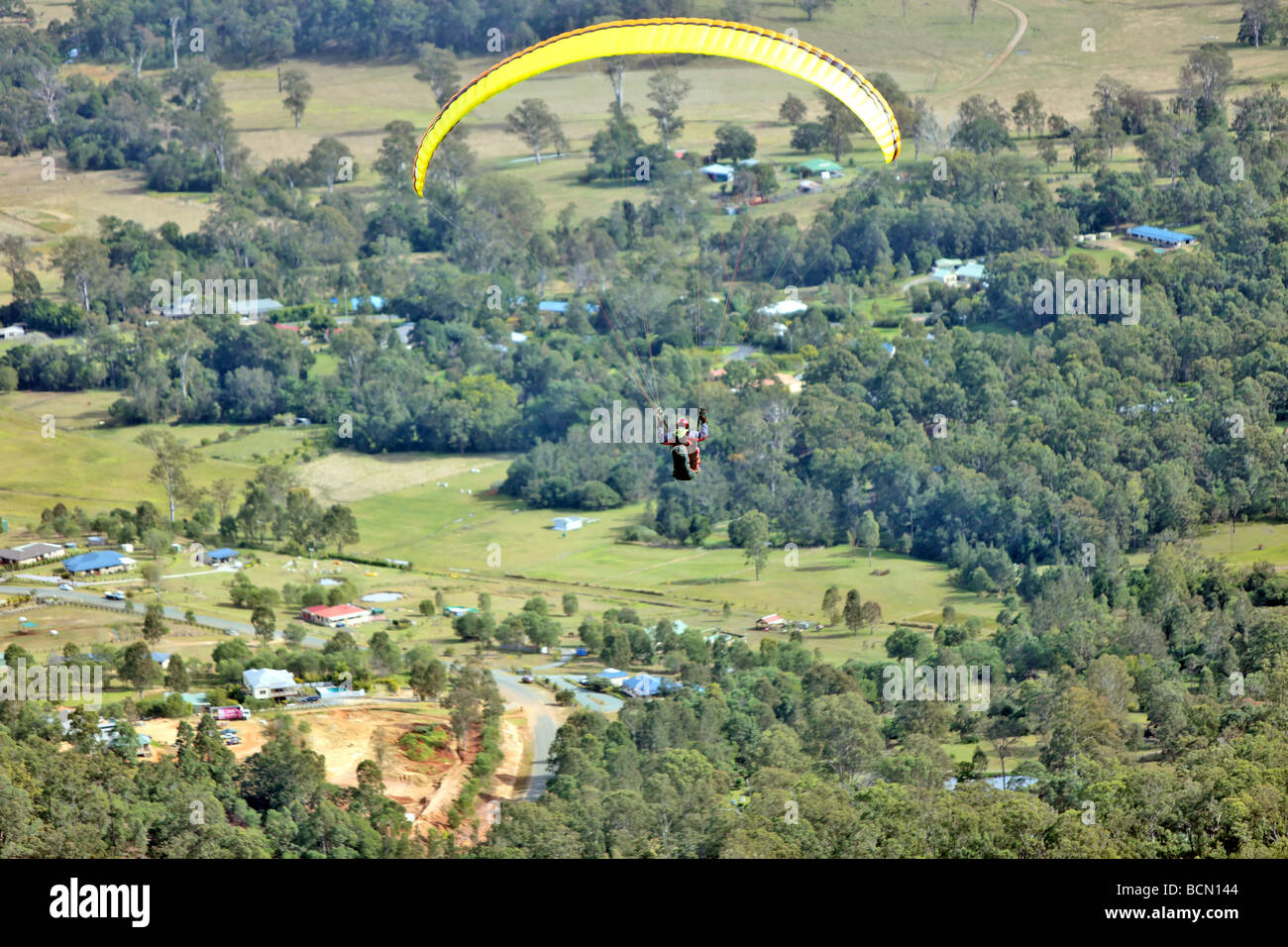 Paragliding with canopy fully inflated and pilot navigating to landing ...