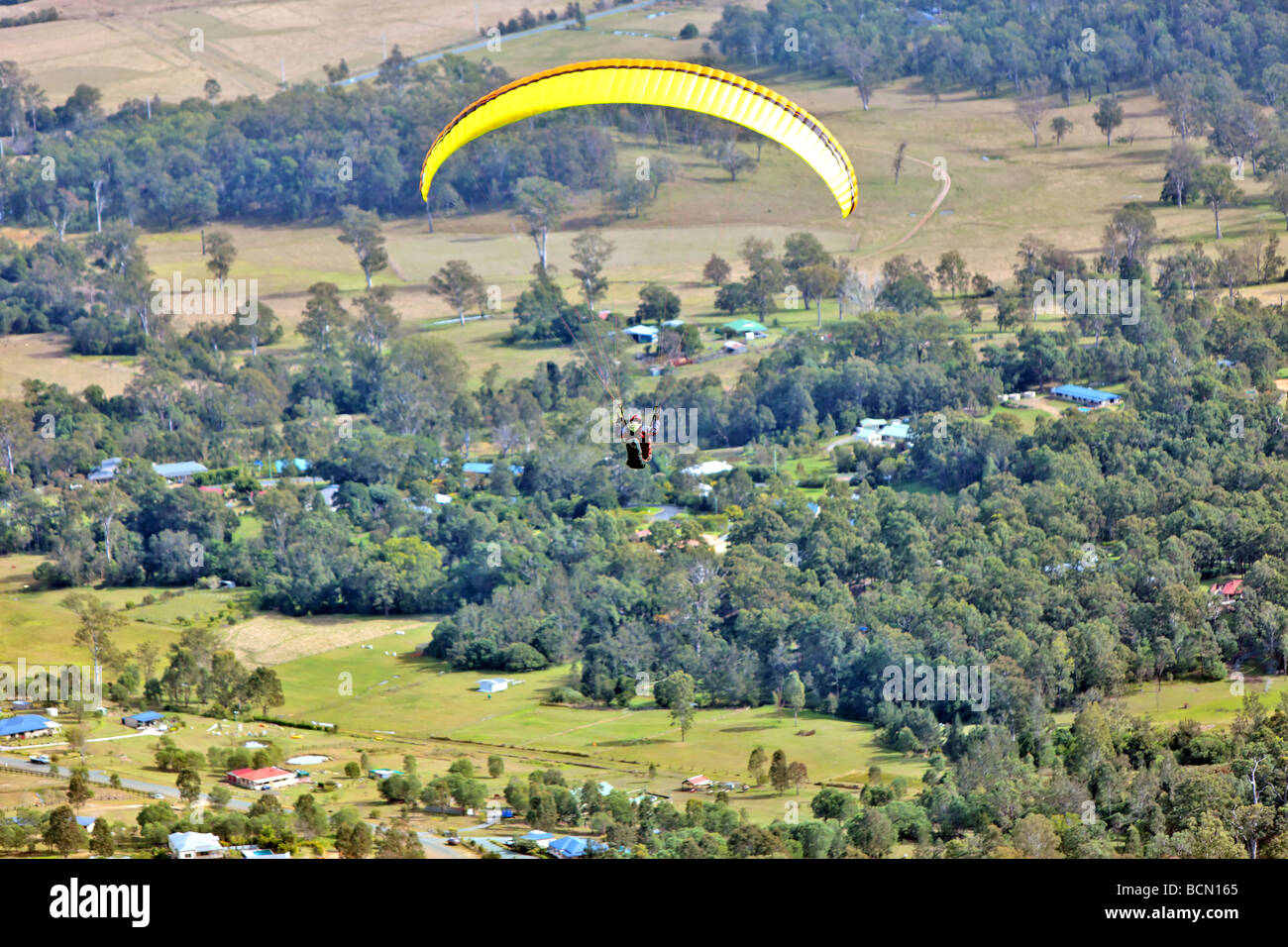 Paragliding with canopy fully inflated and pilot navigating to landing ...