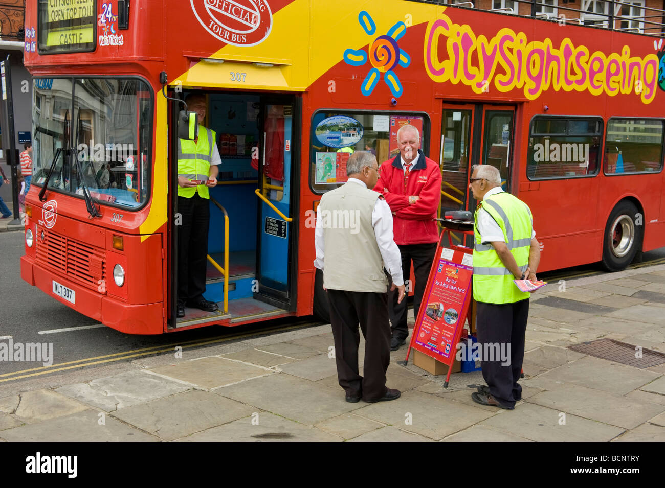 three men chatting outside a parked sightseeing red tour bus in Windsor ...