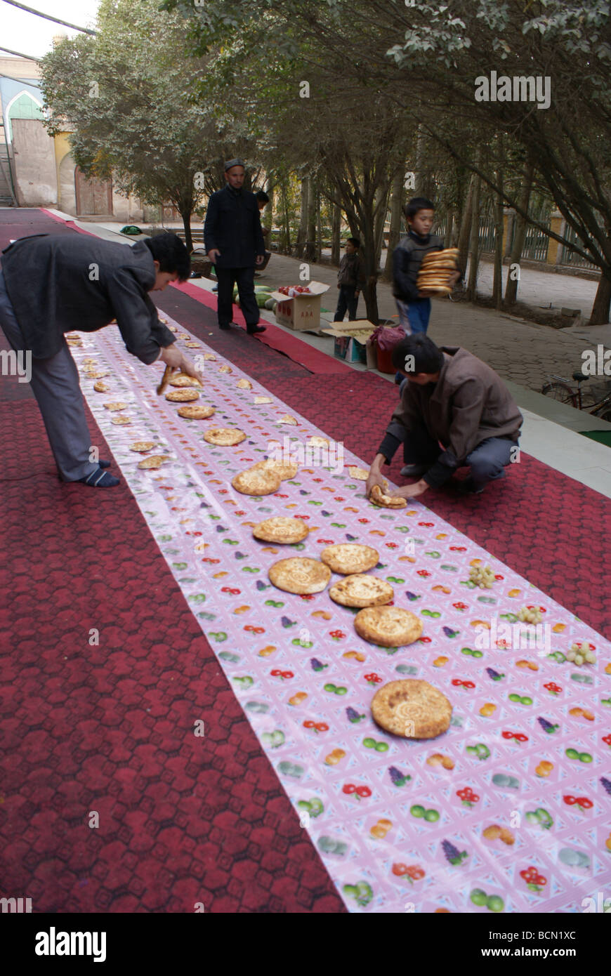Uyghurs arranging food on carpet, which serves as dinning table in the ...