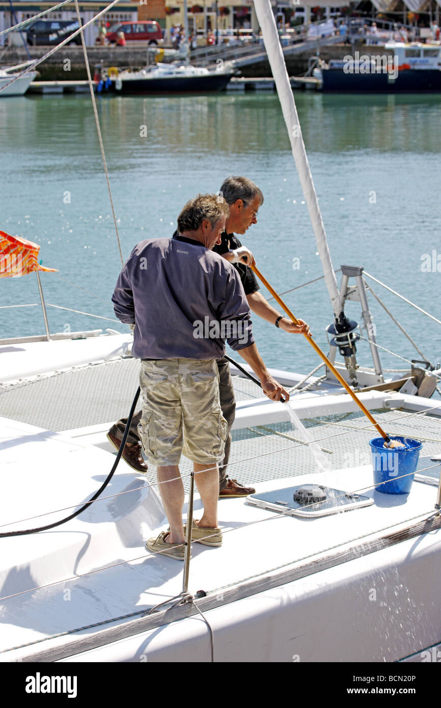Two men washing and cleaning the deck of a Catamaran yacht Stock Photo ...