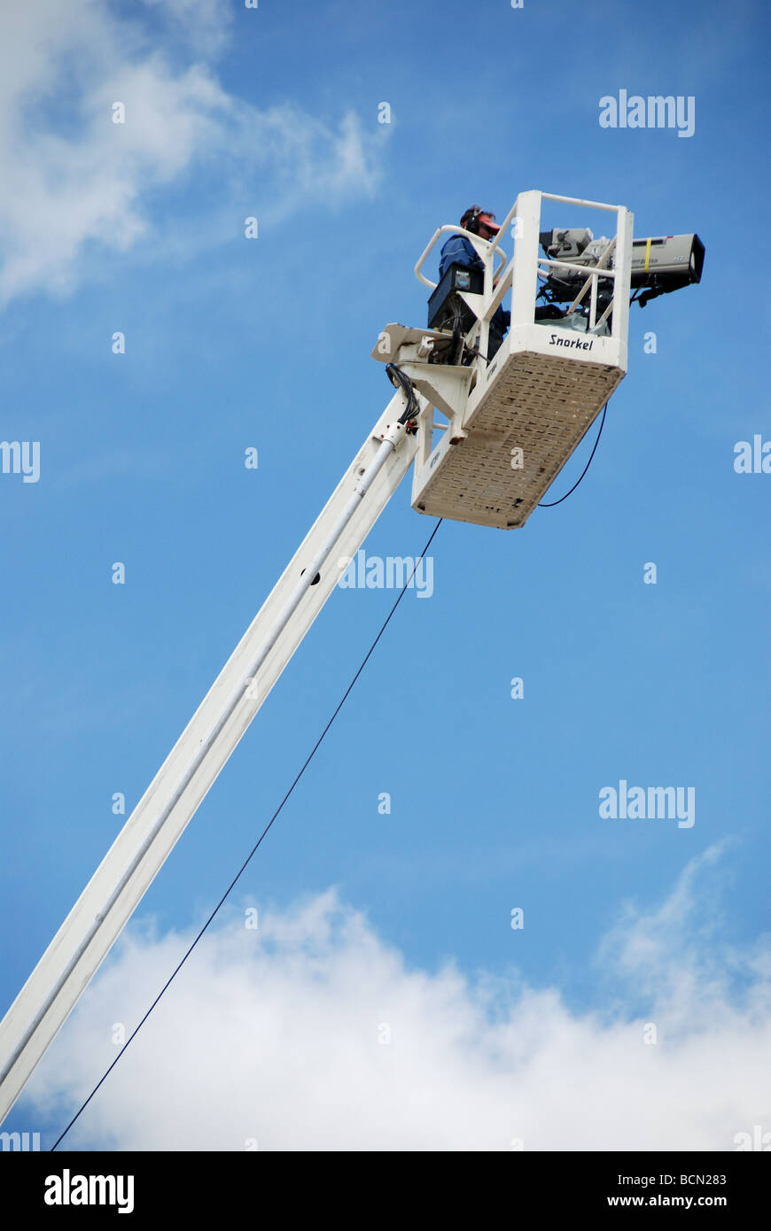A television cameraman on an elevated camera crane at an auto racing ...