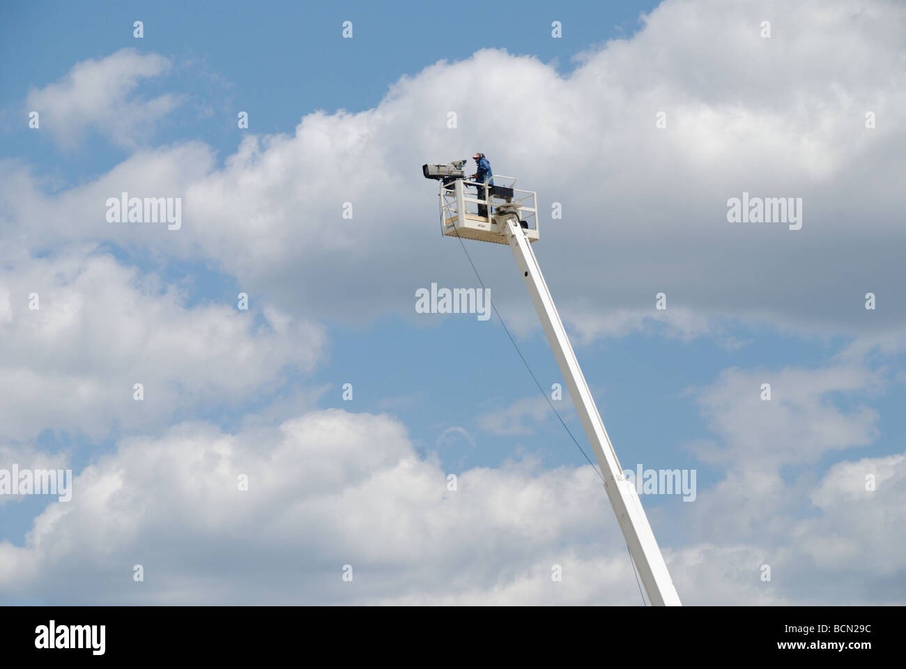 A television cameraman on an elevated camera crane at an auto racing ...