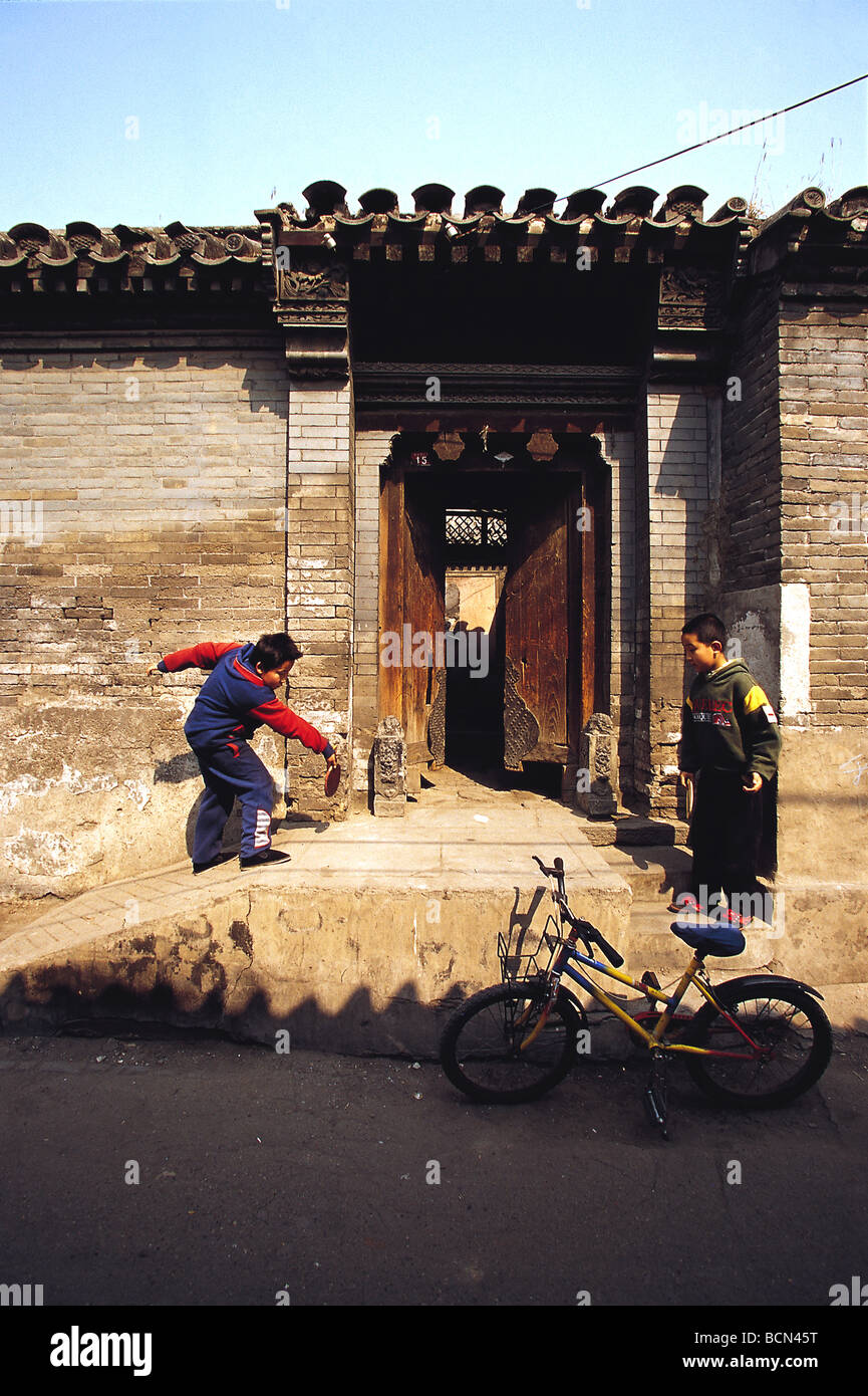 Two boys playing Ping Pang at the door of a traditional courtyard style ...