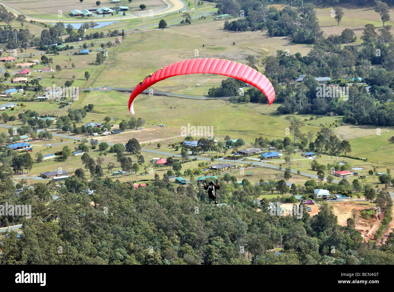 Paragliding with canopy fully inflated and pilot navigating to landing ...