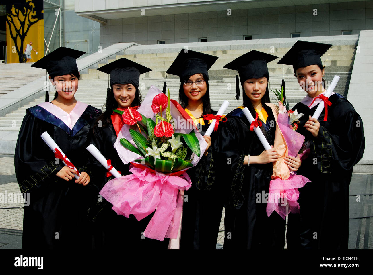 Female university graduates in caps and gowns holding flowers, Shanghai ...