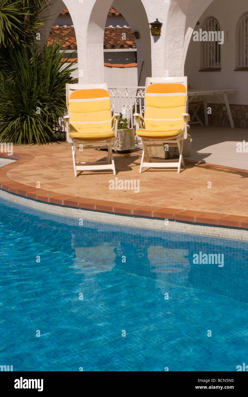 Pale Blue Water of a Swimming Pool with Two Empty Yellow Cushioned ...