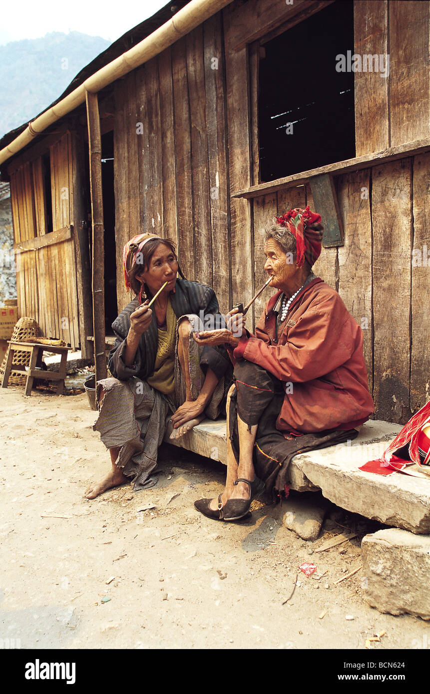 Two Lisu ethnic minority women smoking pipes before their home ...