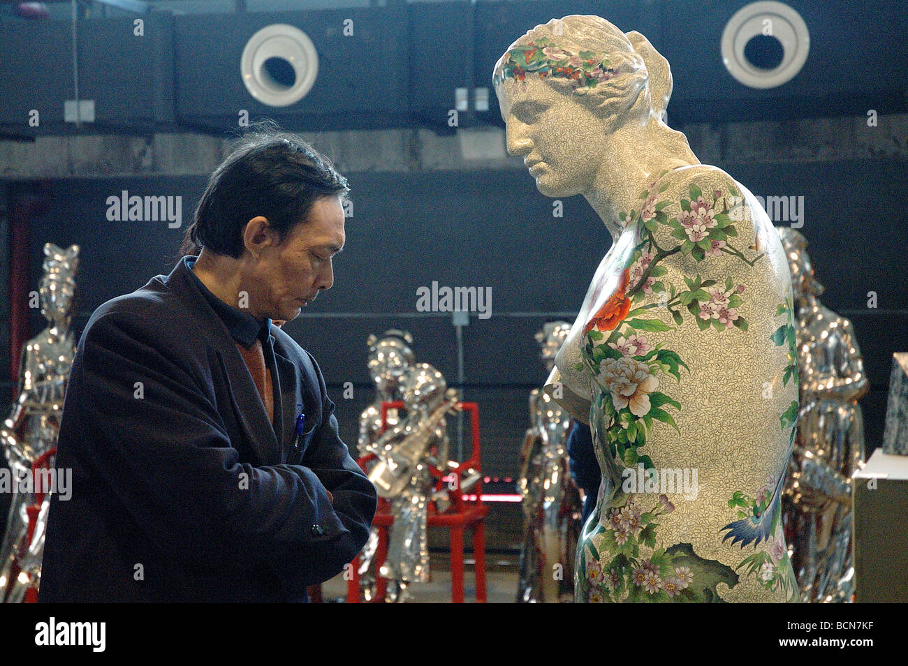 Chinese man studying sculpture of Venus painted with Chinese ...