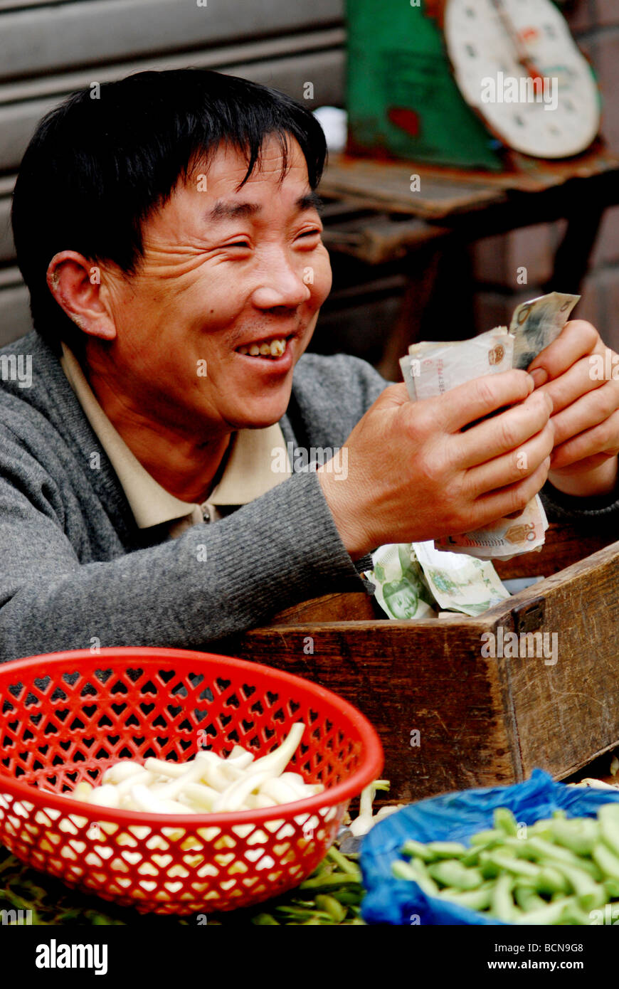 Smiling Chinese vegetable vendor counting money, Chengdu, Szechwan ...