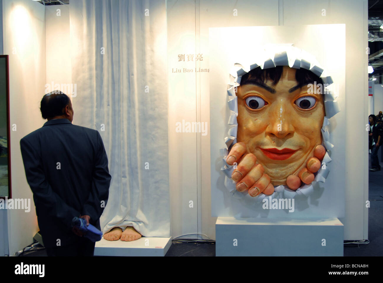 Chinese gallery goer looking at a sculpture by Chinese sculptor Liu Bao ...