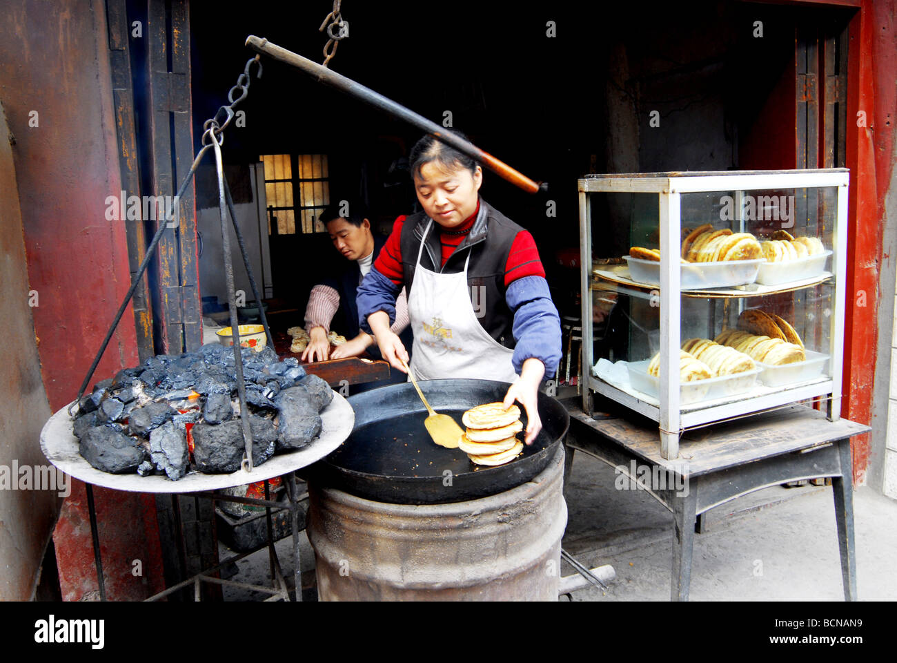Chinese couple roasting Wangcang Guokui bread with stuffing at a ...