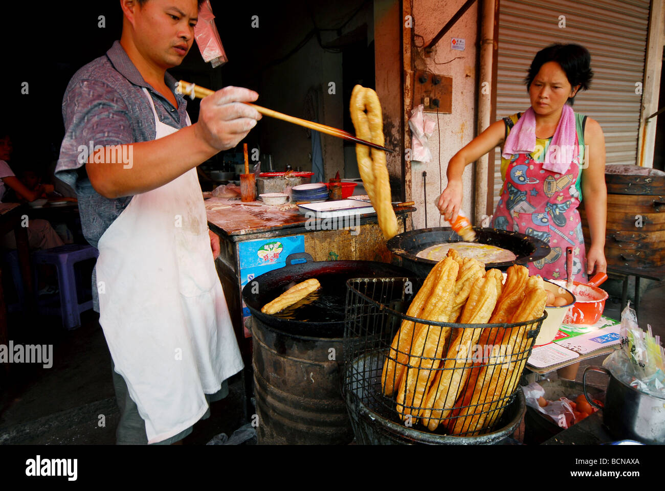 Couple preparing traditional breakfast food in streetside food stall ...