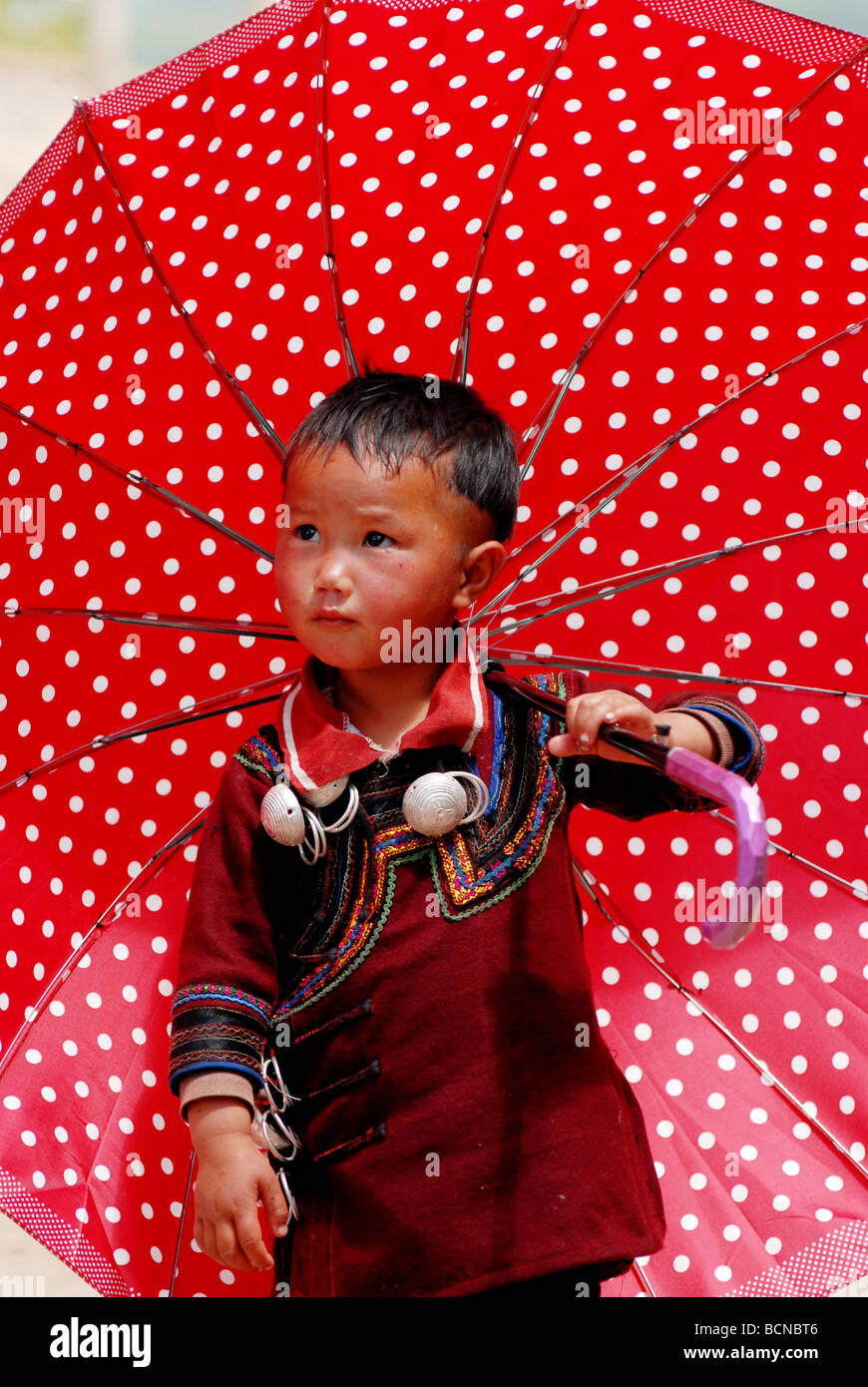 Yi minority boy in traditional costume holding an umbrella, Liangshan ...