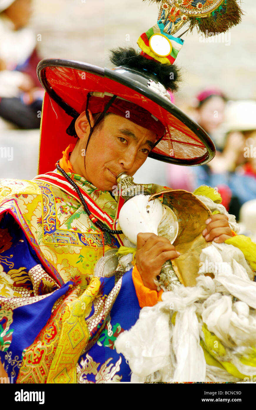 Lama in elaborate costume playing Tibetan Conch Shell Trumpet during ...