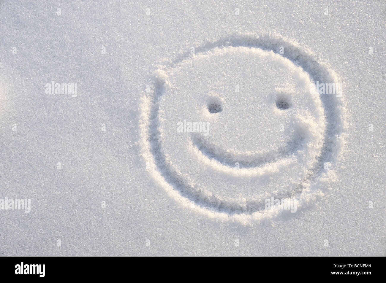 Smiley face drawn in snow in a sunny winter day Stock Photo - Alamy