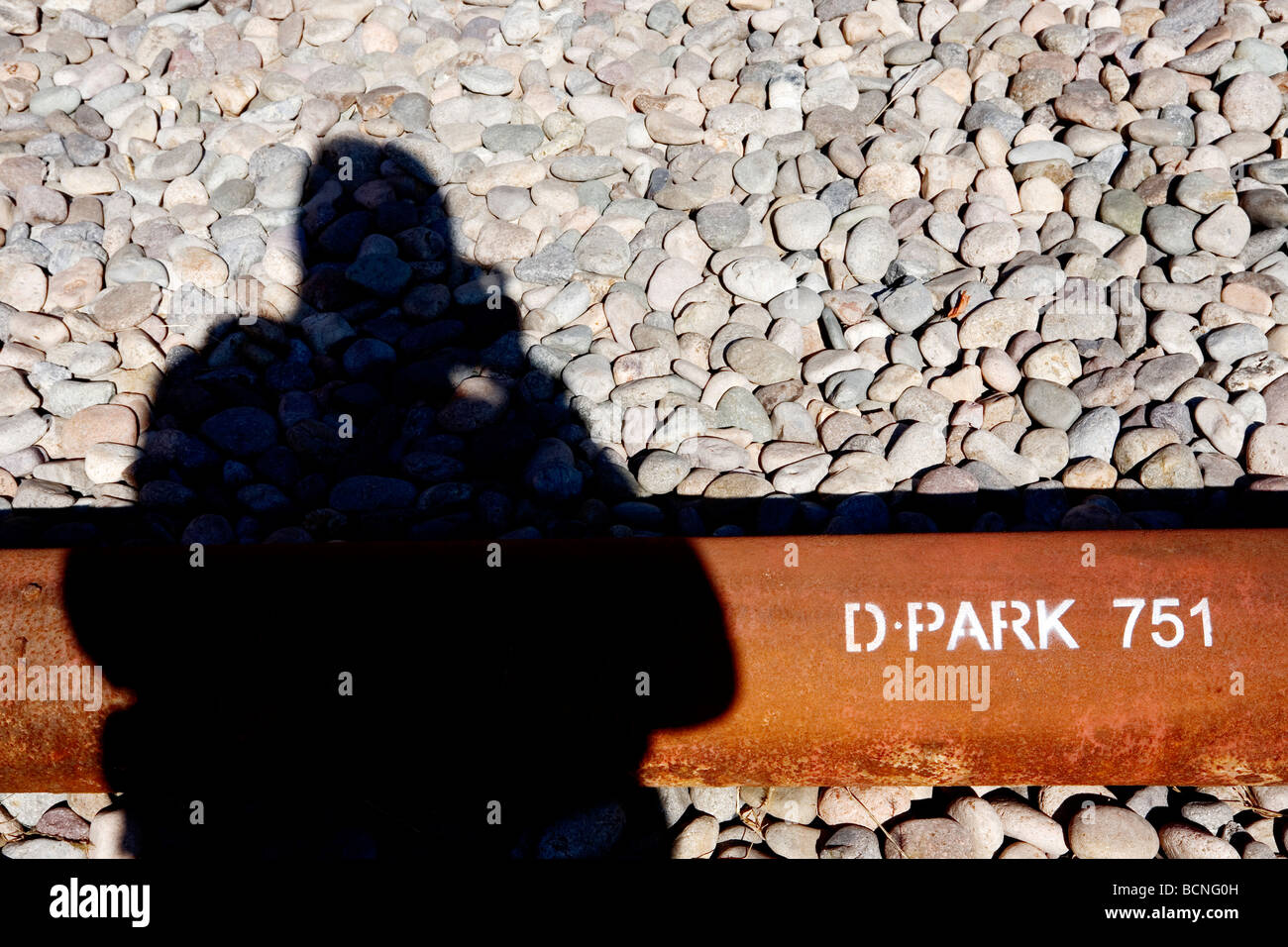 Shadow of a tourist taking picture of rusted pipe on pebbles in D-PARK ...