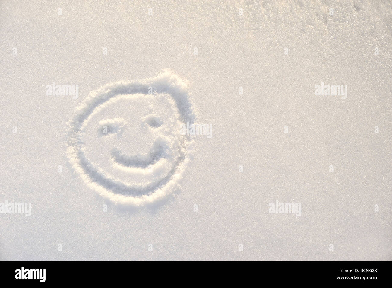 Smiley face drawn in snow in a sunny winter day Stock Photo - Alamy