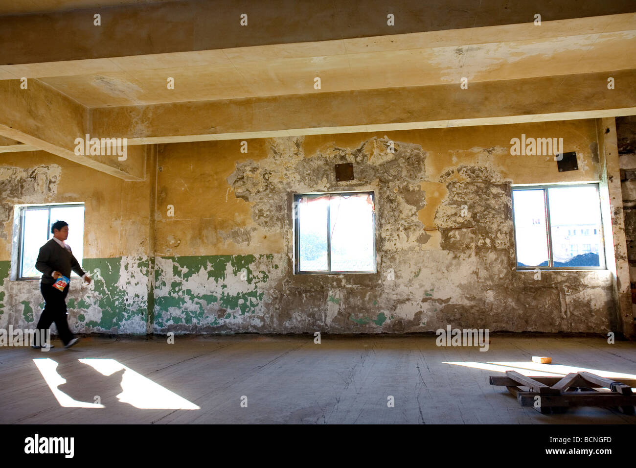 Chinese man walking in the emptied factory floor of an old factory, 798 ...