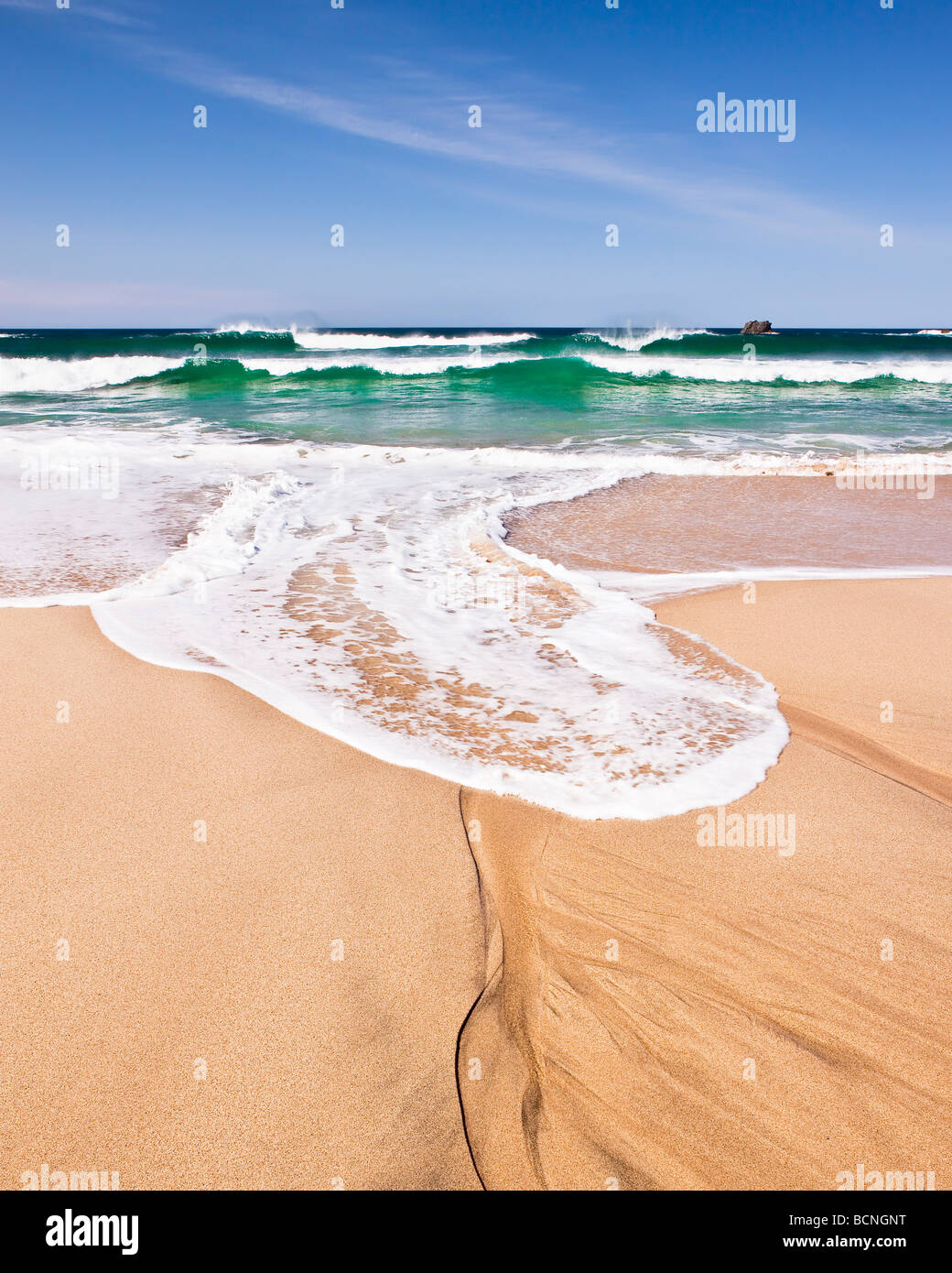 Surf rolls up beach Stock Photo - Alamy