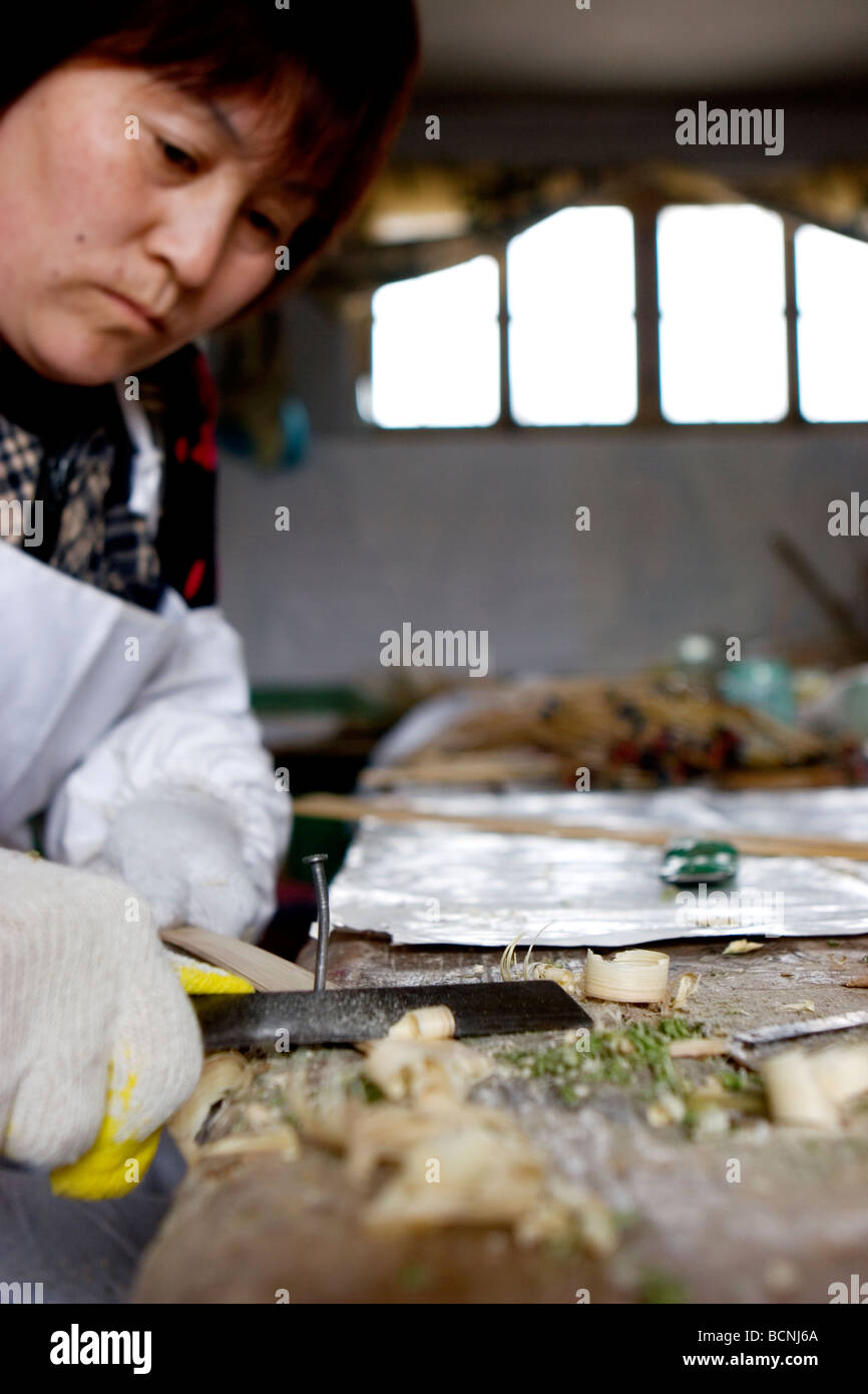 Kite artist scraping bamboo strip to make kite, Weifang, Shandong ...