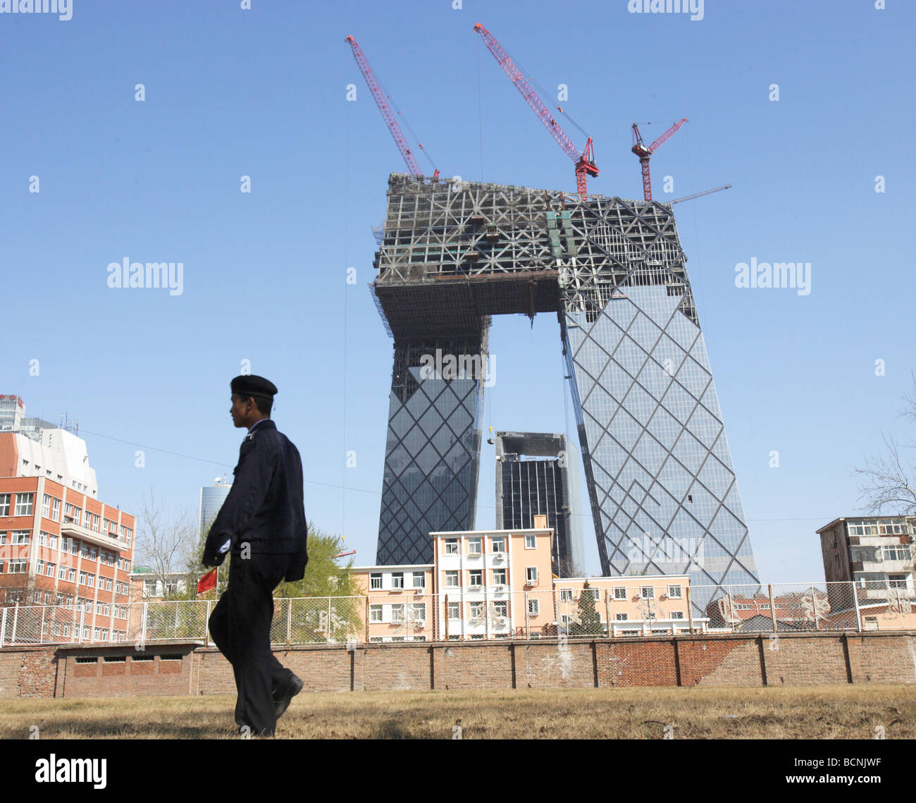 Security guard walking pass the CCTV Tower still under construction ...