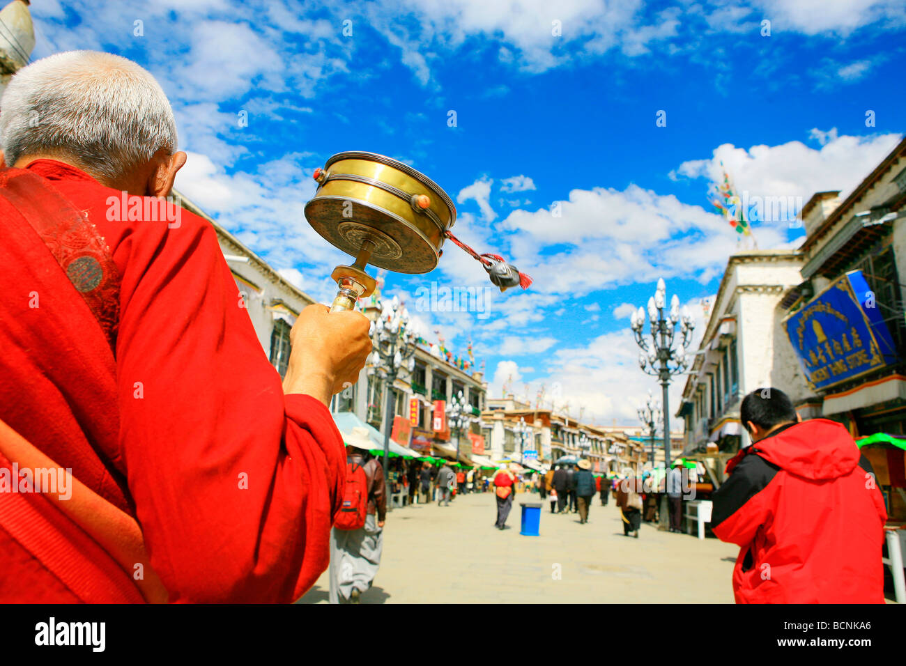 Old lama with praying wheel walking on the street of Lhasa, Tibet ...