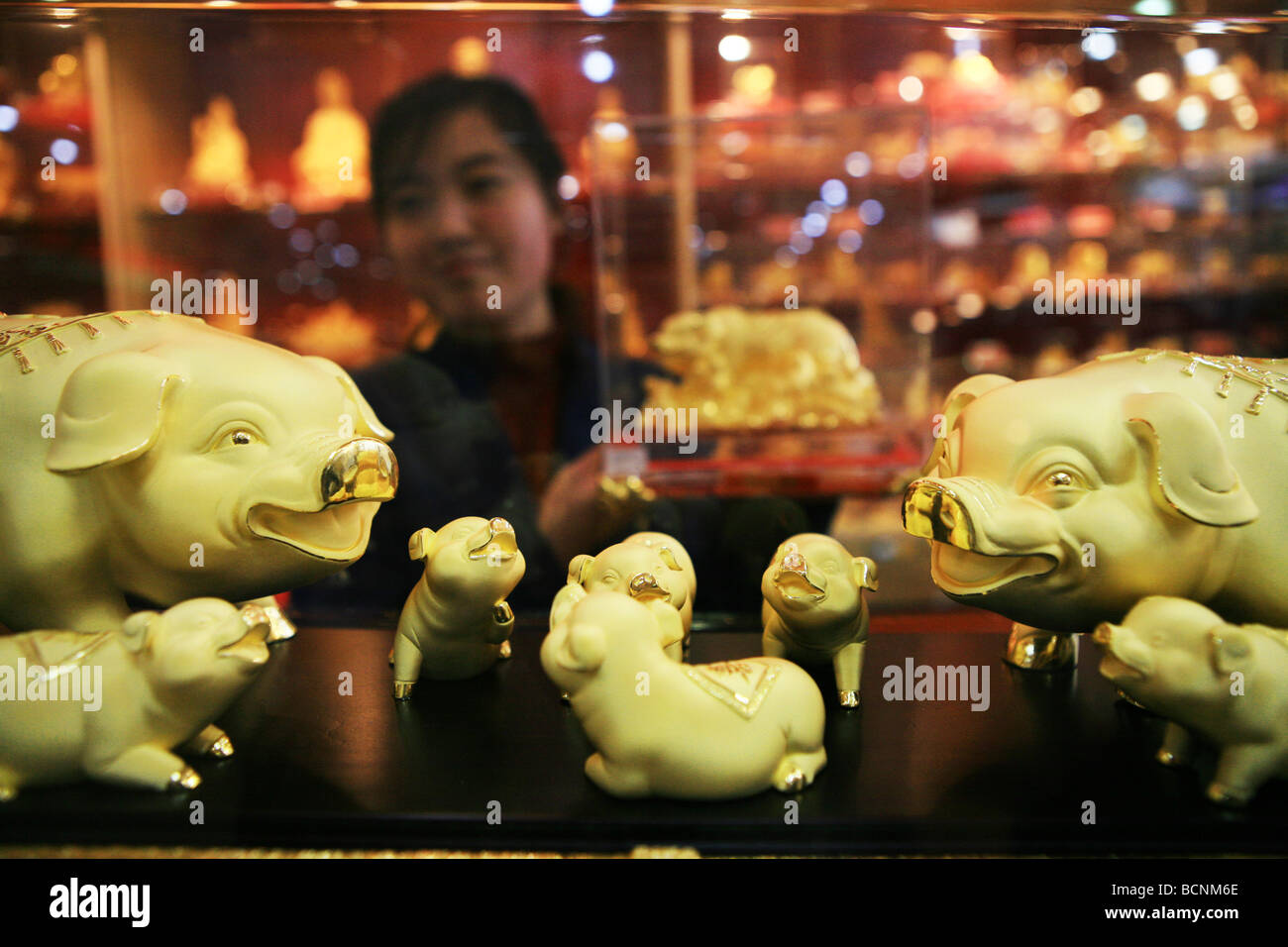 Statue of smiling pigs in gold in jewelry shop window display, Beijing ...