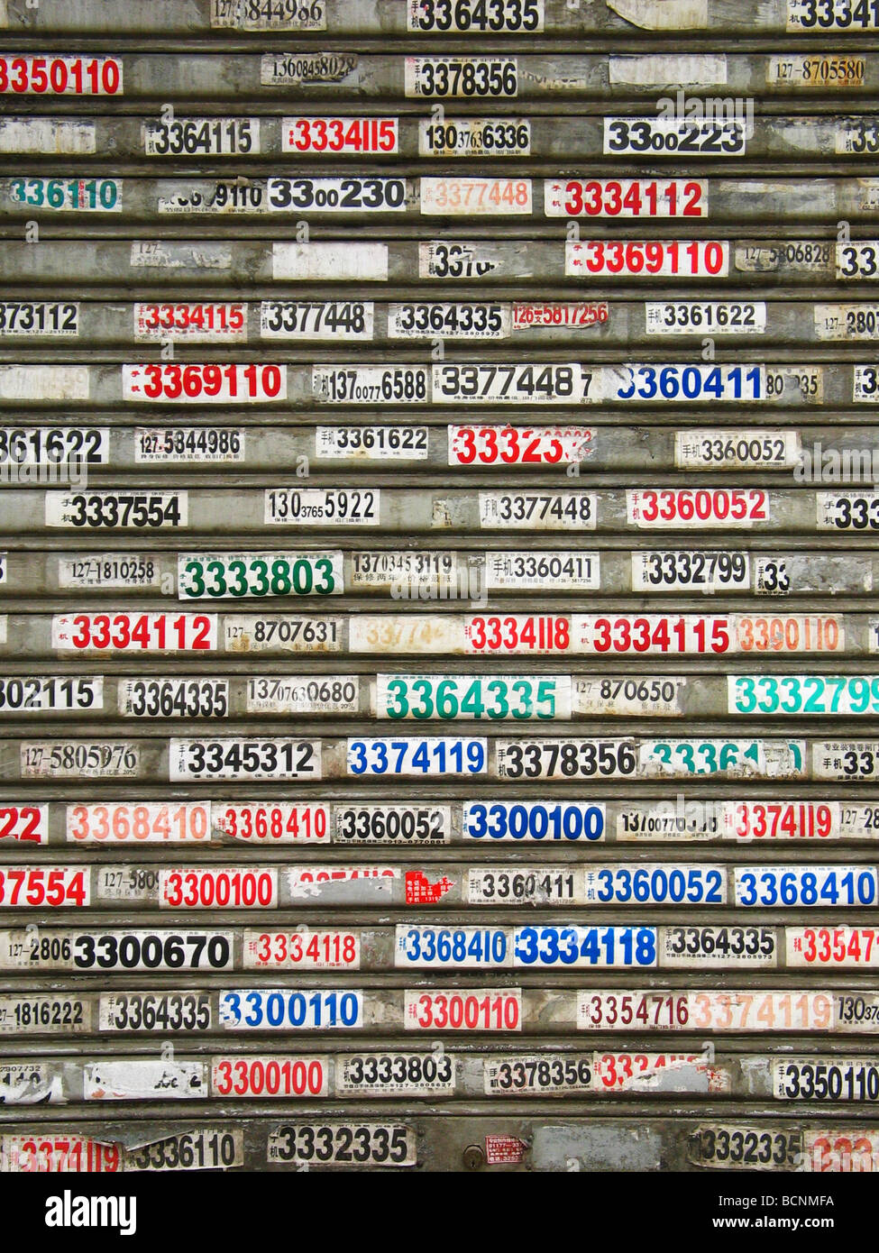 Layers of telephone numbers stickers on window blinds of a local store ...