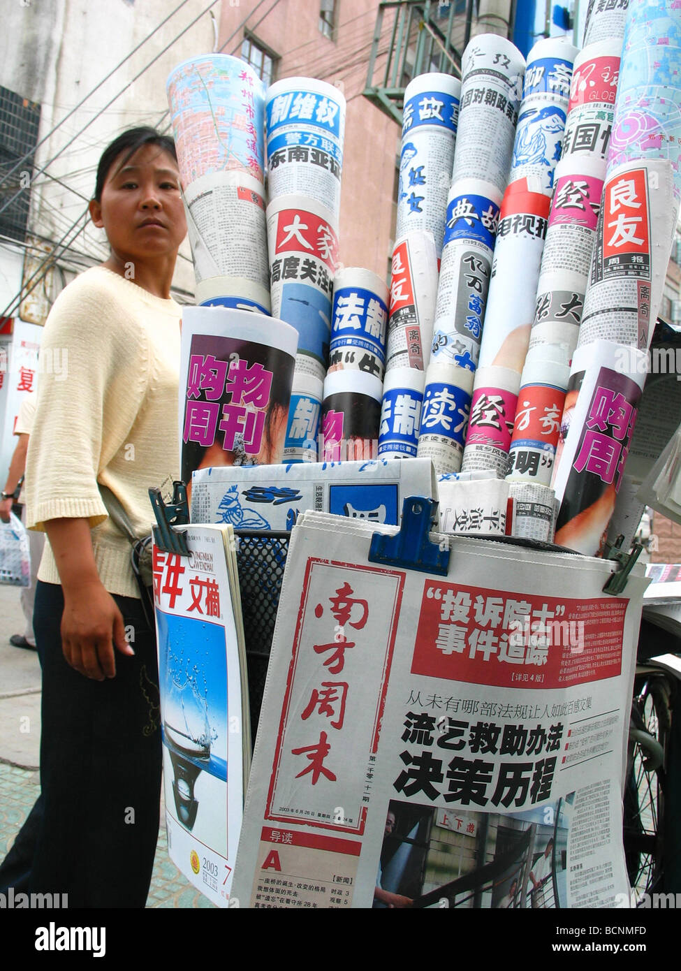 Woman selling large assortment of daily newspapers addressing social ...