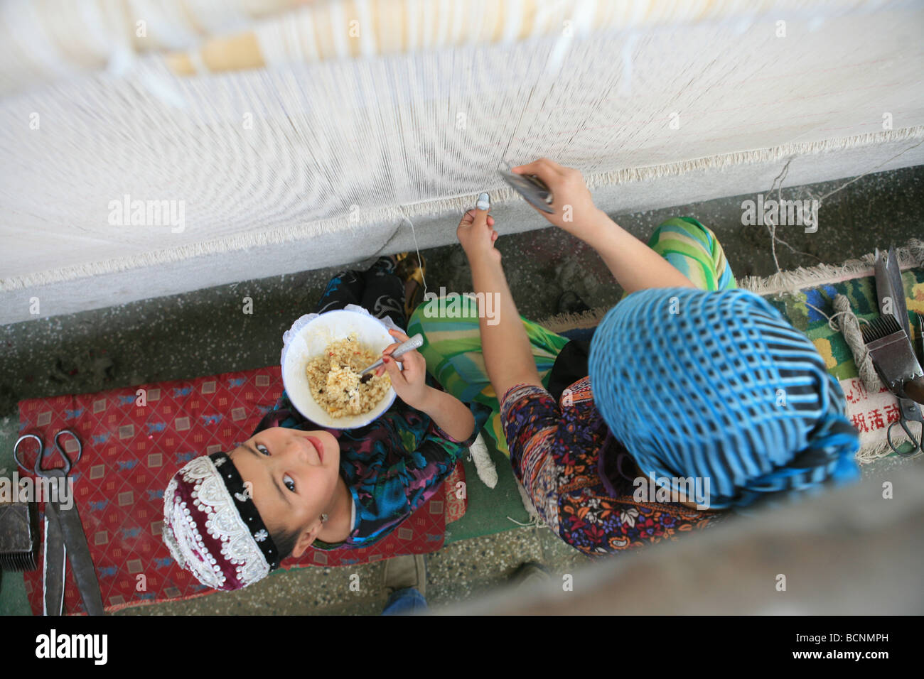 Young Uyghur woman weaving wool carpet, Hotan, Xinjiang Uyghur ...