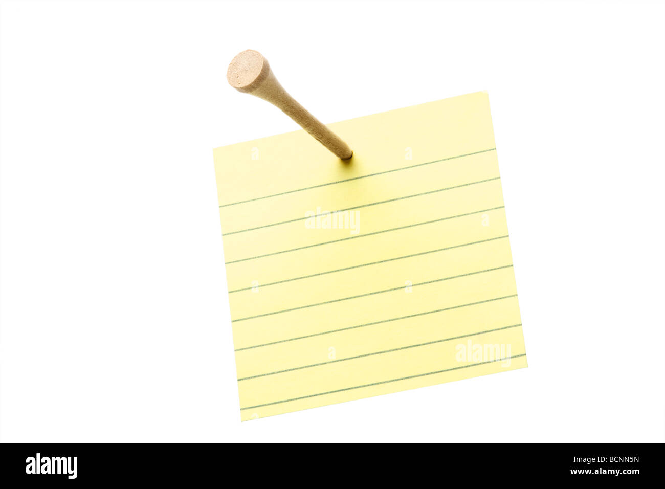 Lined yellow sticky note nailed with wood golf tee to white background ...