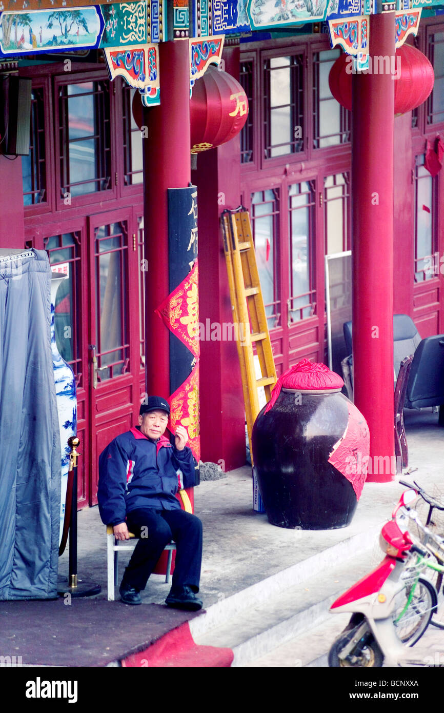 Chinese man sitting in front of a wine store, Gulou Street, Tianjing ...