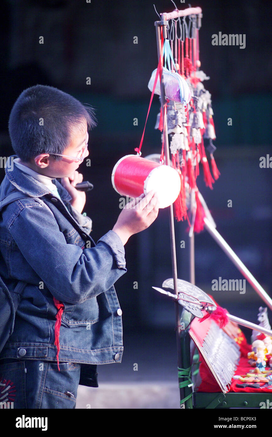 Chinese boy with glasses checking out traditional toys sold on a toy ...