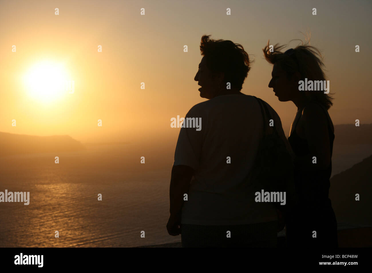 Visitors watch the sunset in Fira on the island of Santorini in the ...