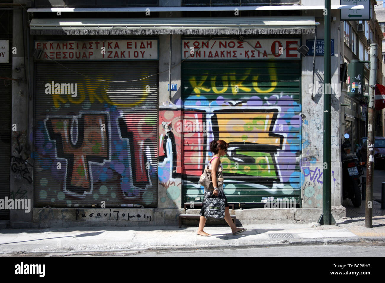 A woman walks through graffitied city streets under the Acropolis in ...